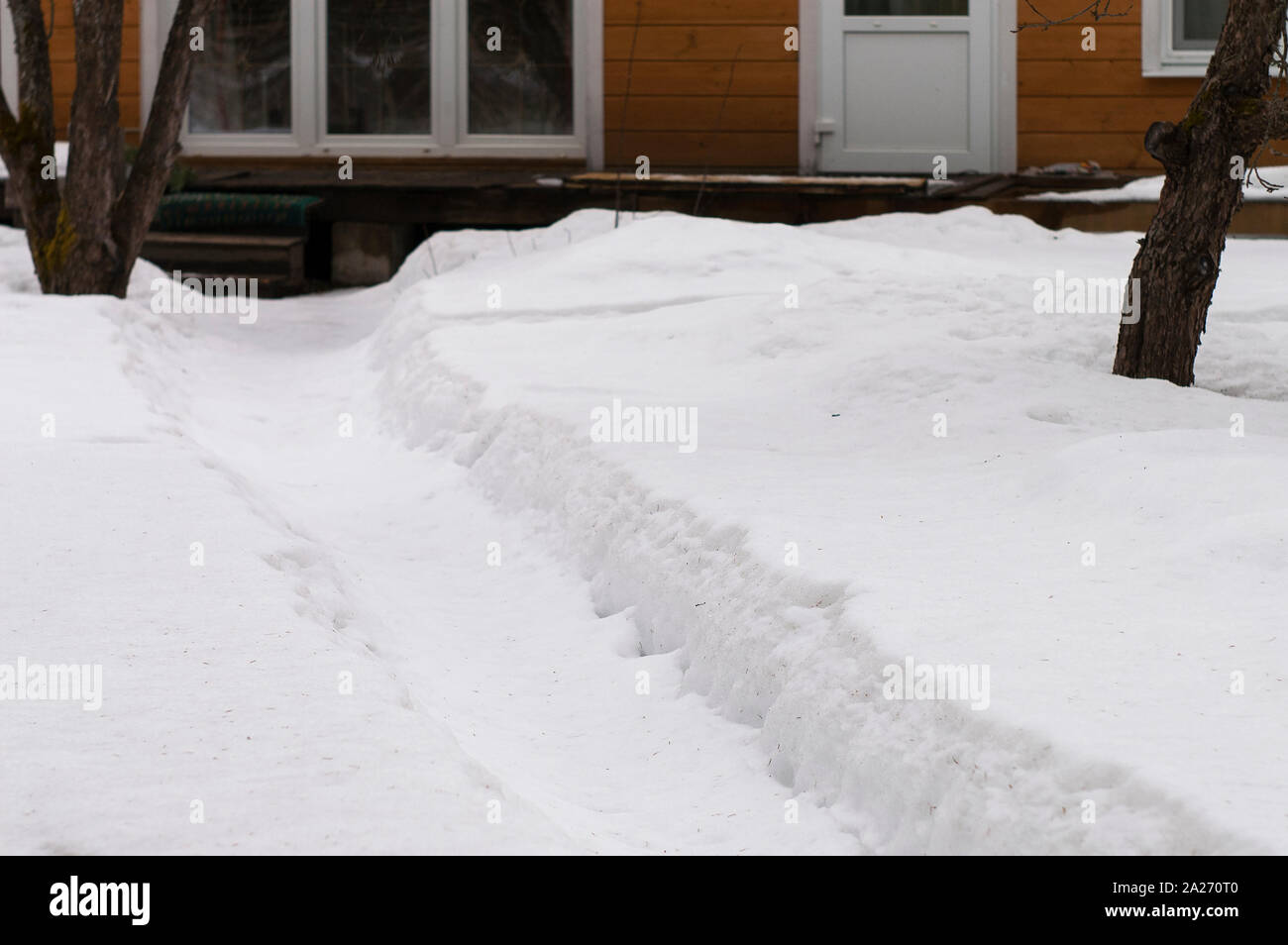 Snow swept footpath leading to the wooden house, winter outdoor shot ...