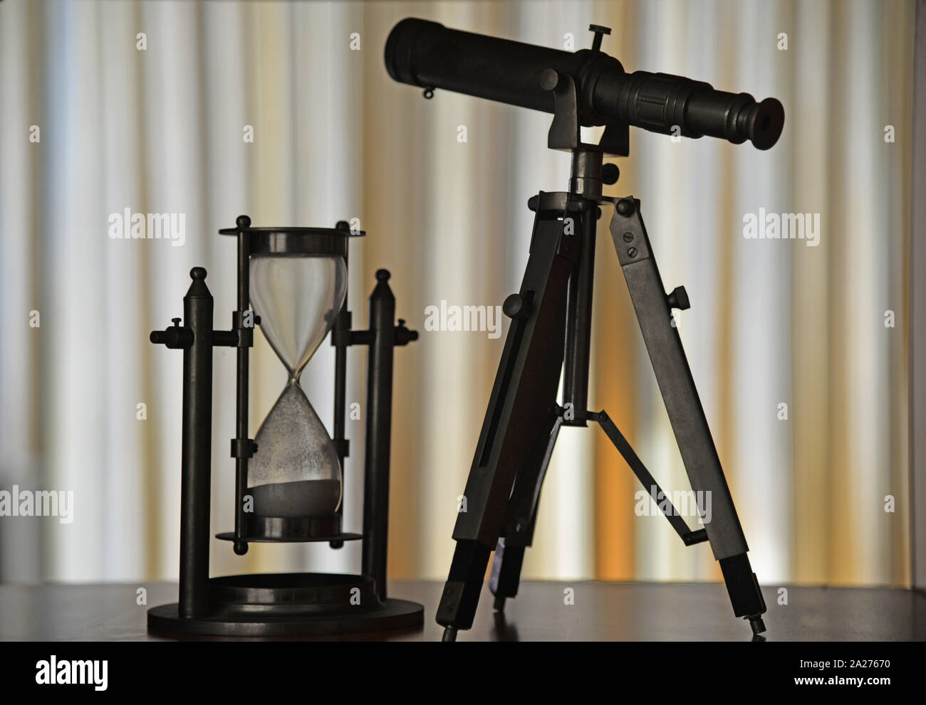 Silhouettes of a Hourglass and a telescope on a bookcase shelf. Concept ...