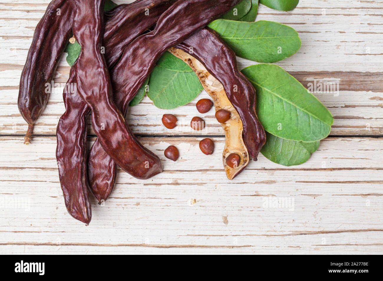 Carob top view. Organic carob pods with seeds and leaves on white ...