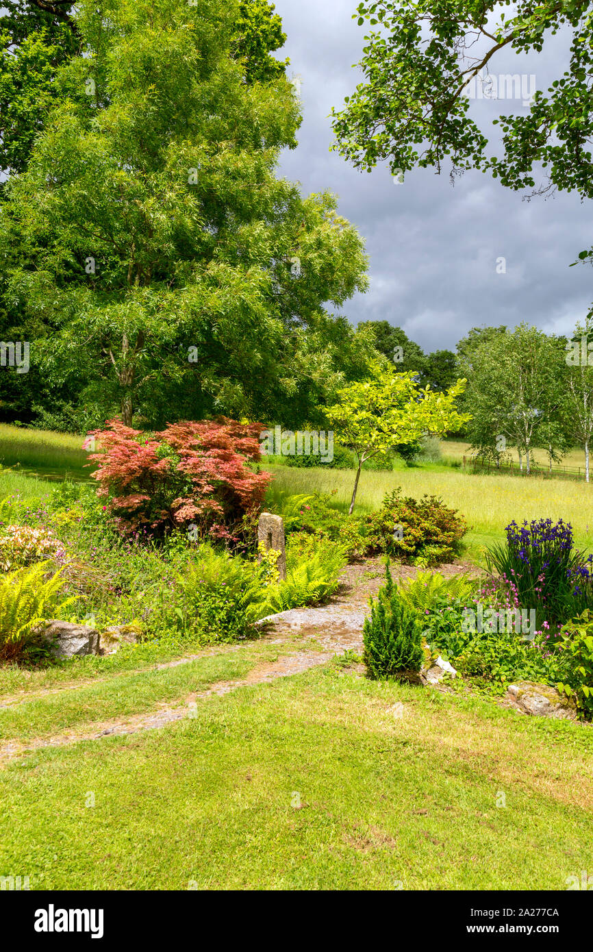Colourful foliage and flowering shrubs and trees planted around an old ...