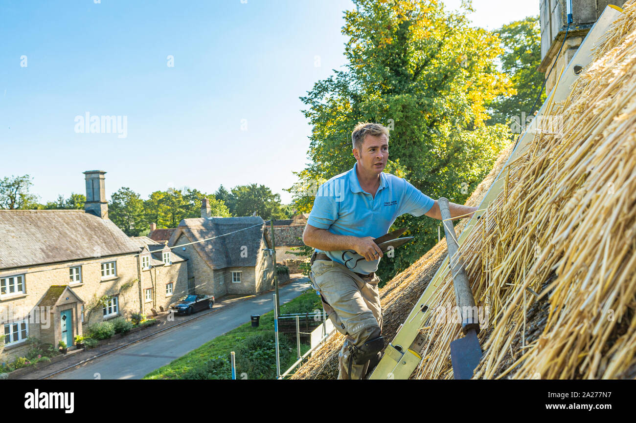 A Master Thatcher working on the roof of a village cottage repairing ...