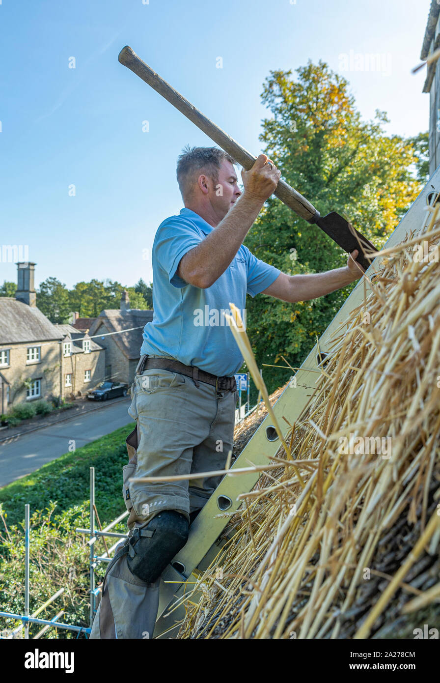 A Master Thatcher working on the roof of a village cottage repairing ...