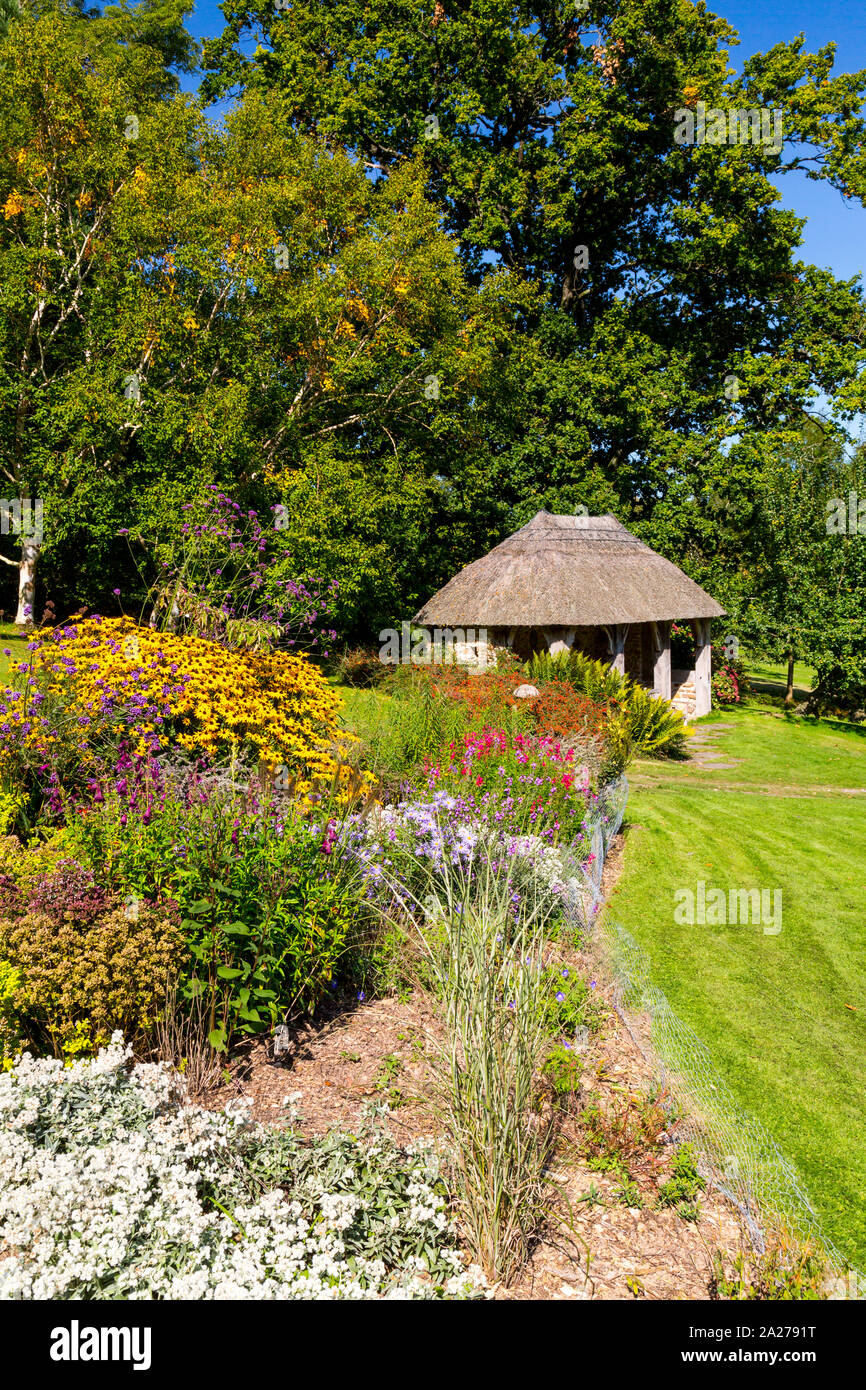 A mixed herbaceous border full of summer colour next to the thatched ...