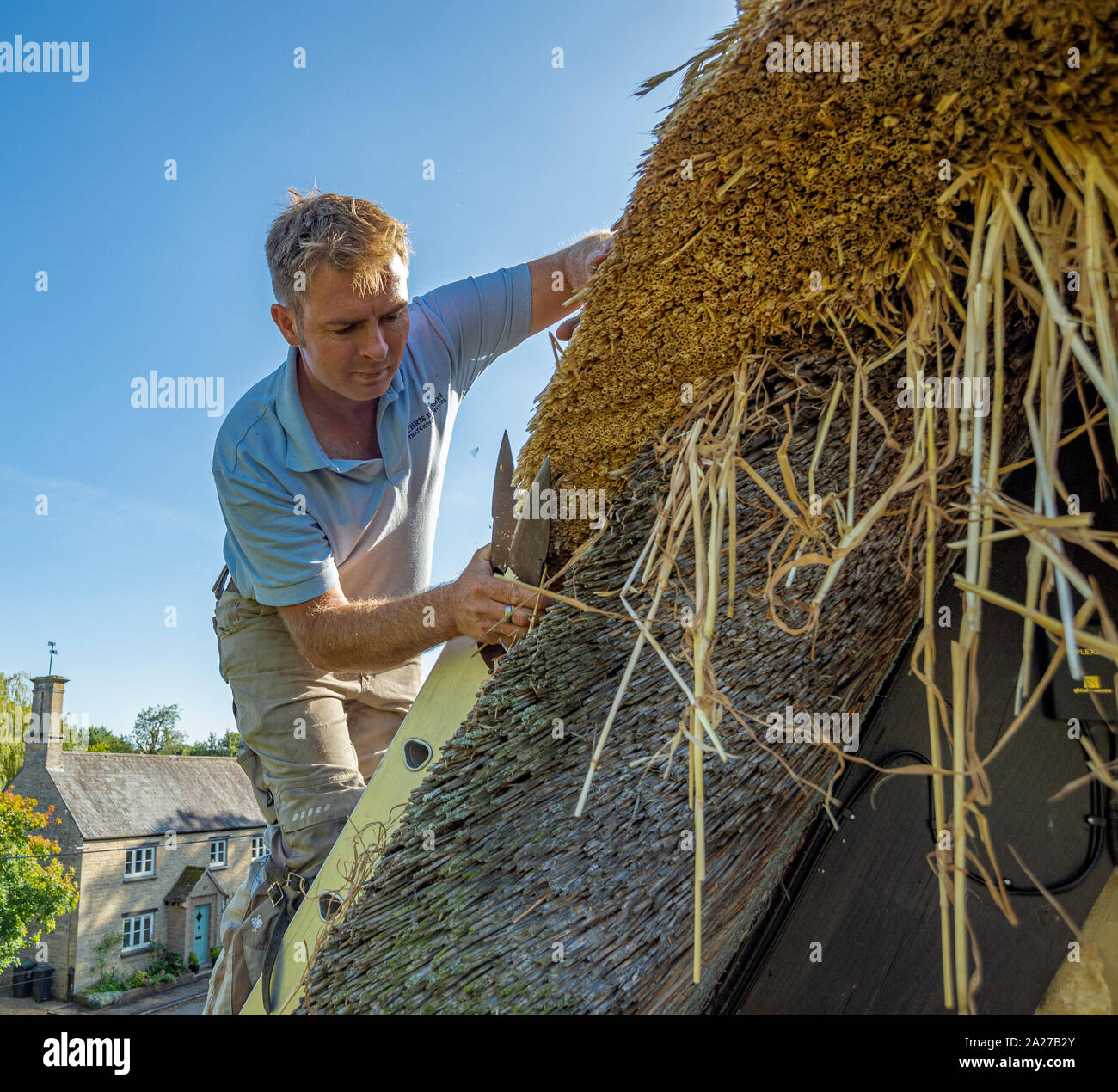 A Master Thatcher working on the roof of a village cottage repairing ...