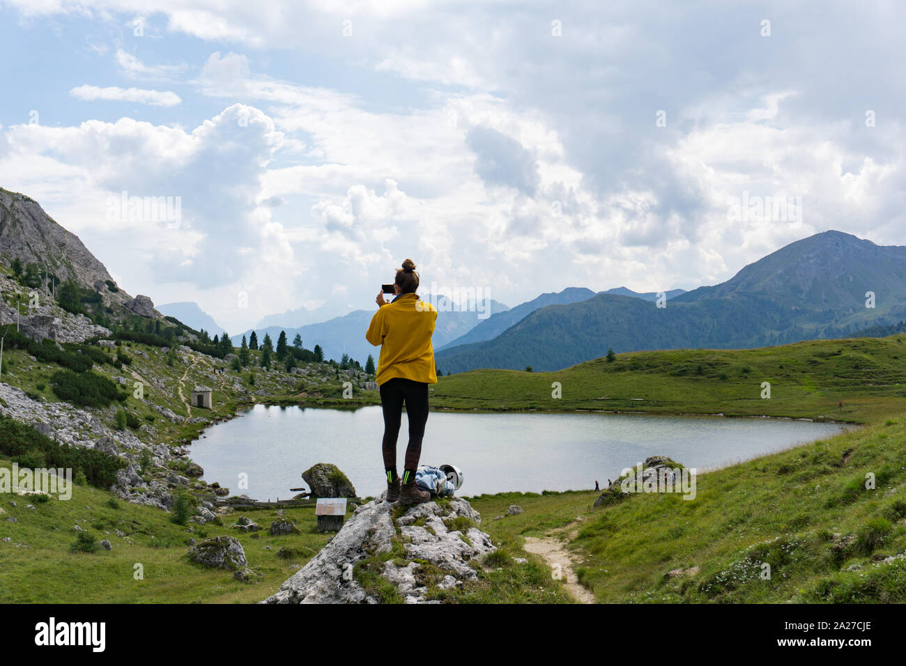 female mountain climber stands on a boulder and takes photographs of ...