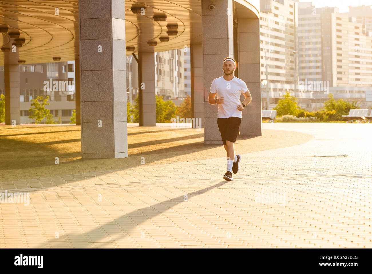 Attractive fit man running in the city at sunset. Fitness, workout ...