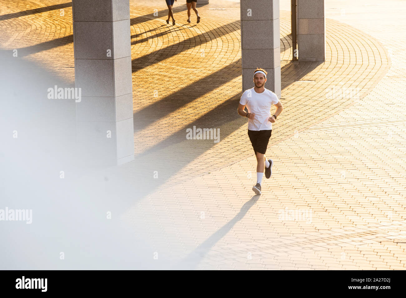 Attractive fit man running in the city at sunset. Fitness, workout ...