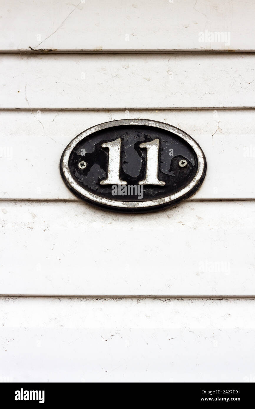 House number 11 in an oval sign on a wall of white wooden planks Stock ...