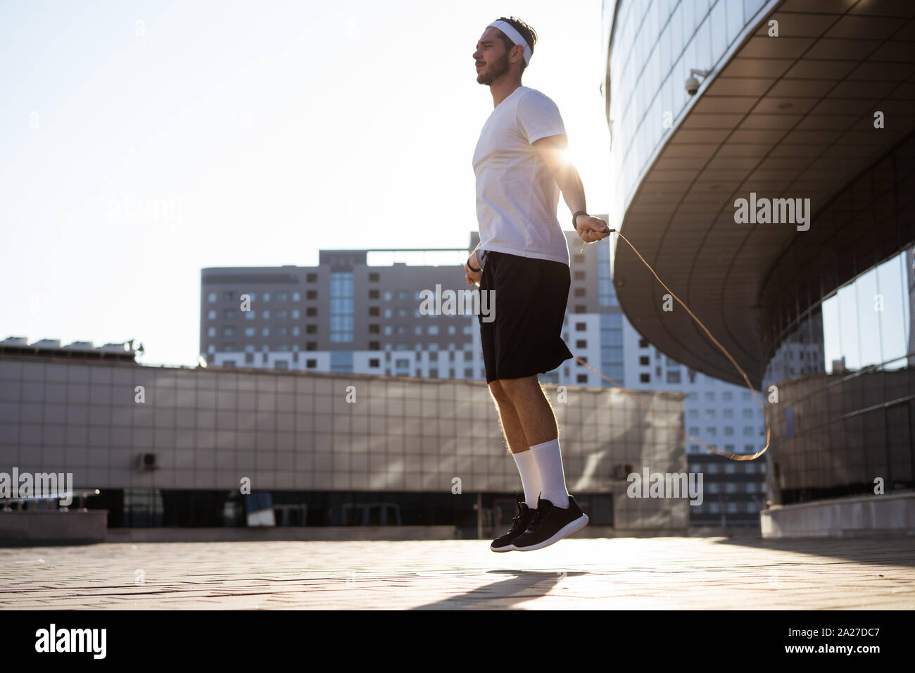 Young man jumping rope outside Stock Photo - Alamy