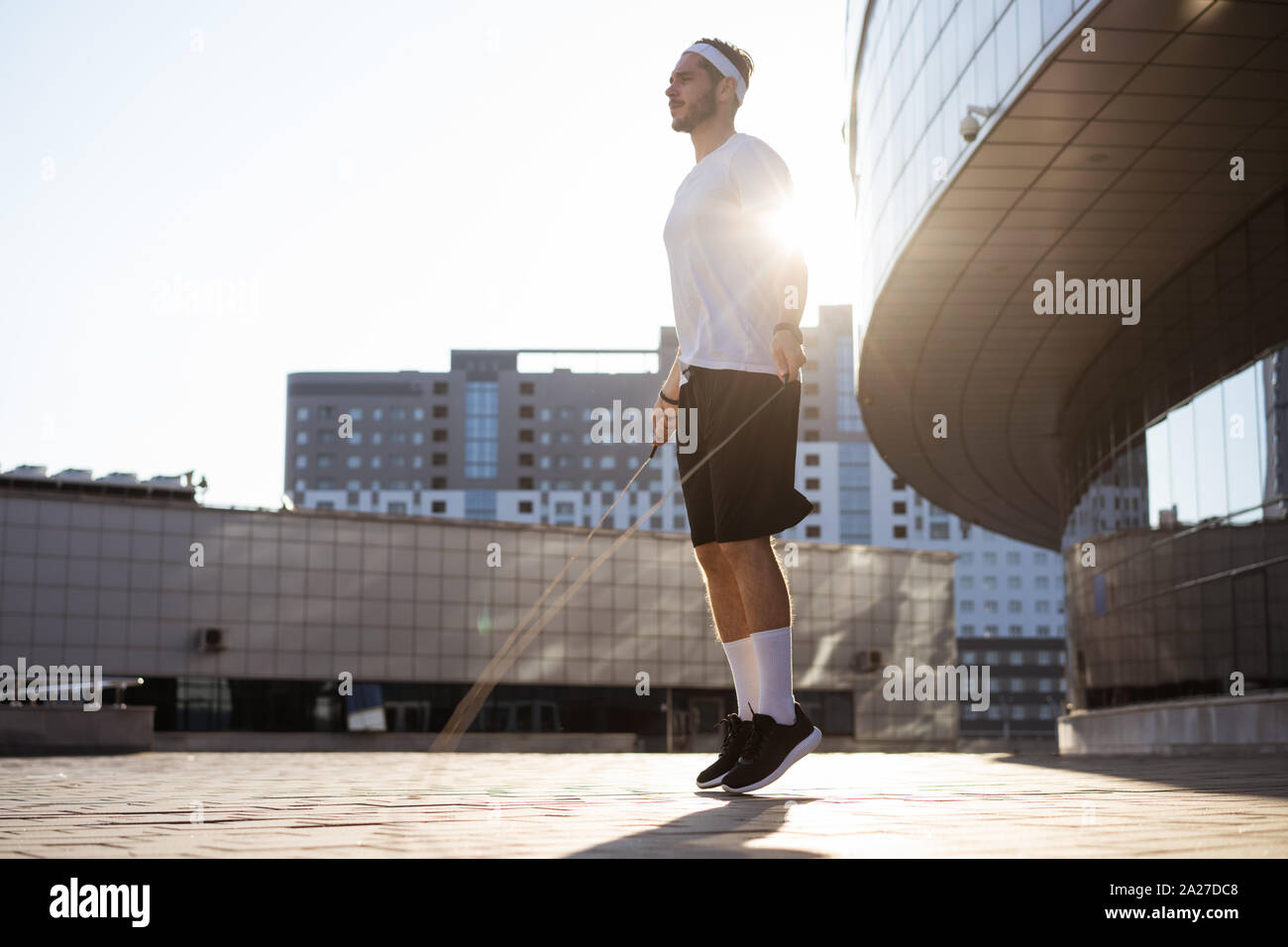 Young man jumping rope outside Stock Photo - Alamy