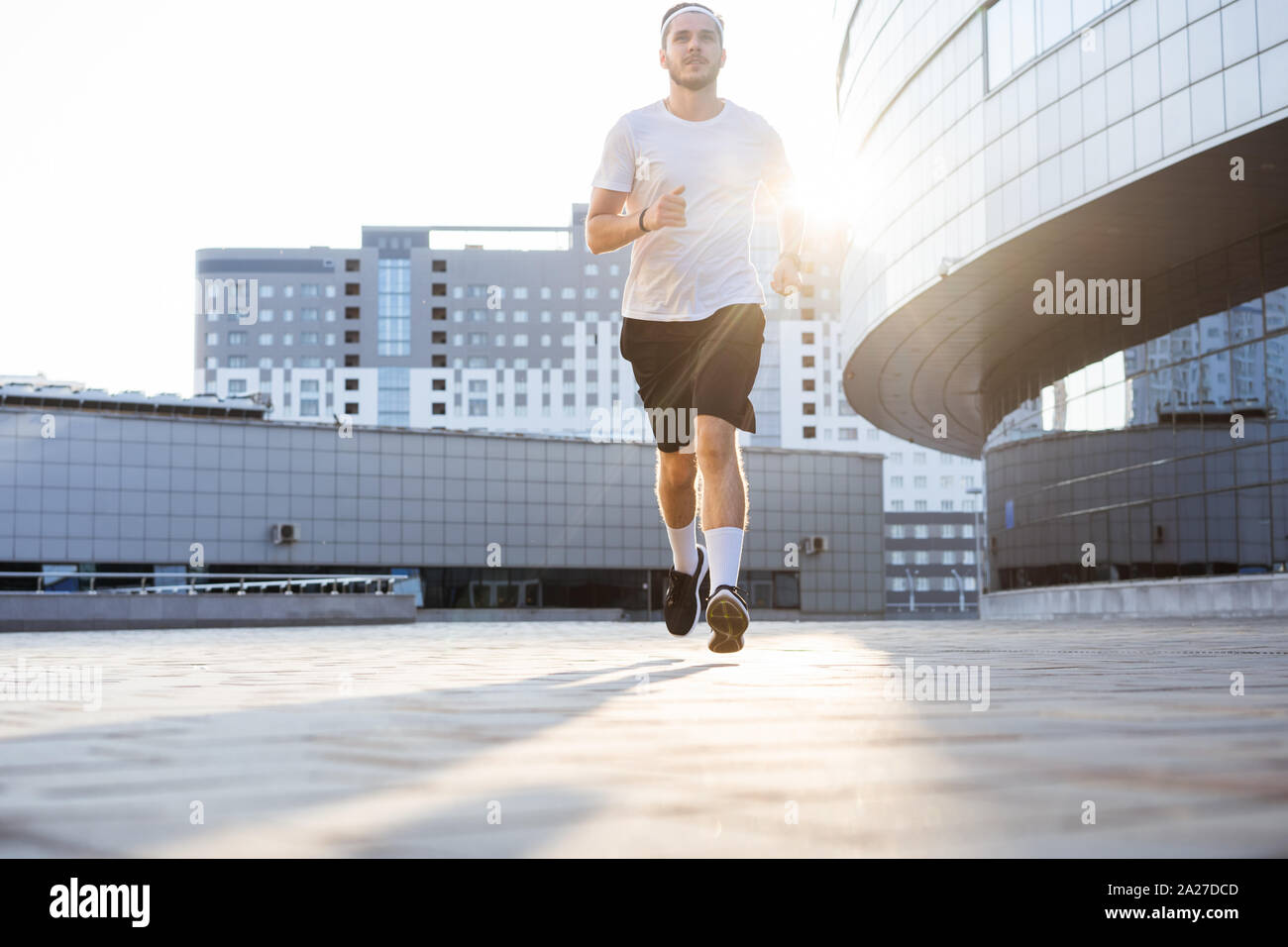 Attractive fit man running in the city at sunset. Fitness, workout ...