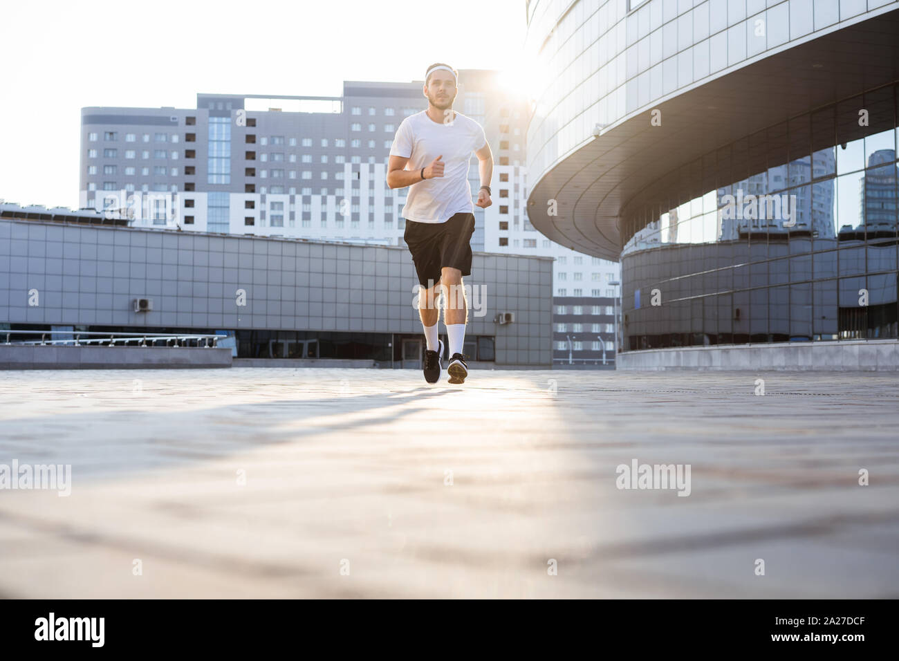 Attractive fit man running in the city at sunset. Fitness, workout ...