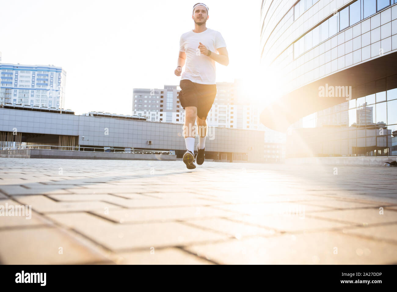 Attractive fit man running in the city at sunset. Fitness, workout ...