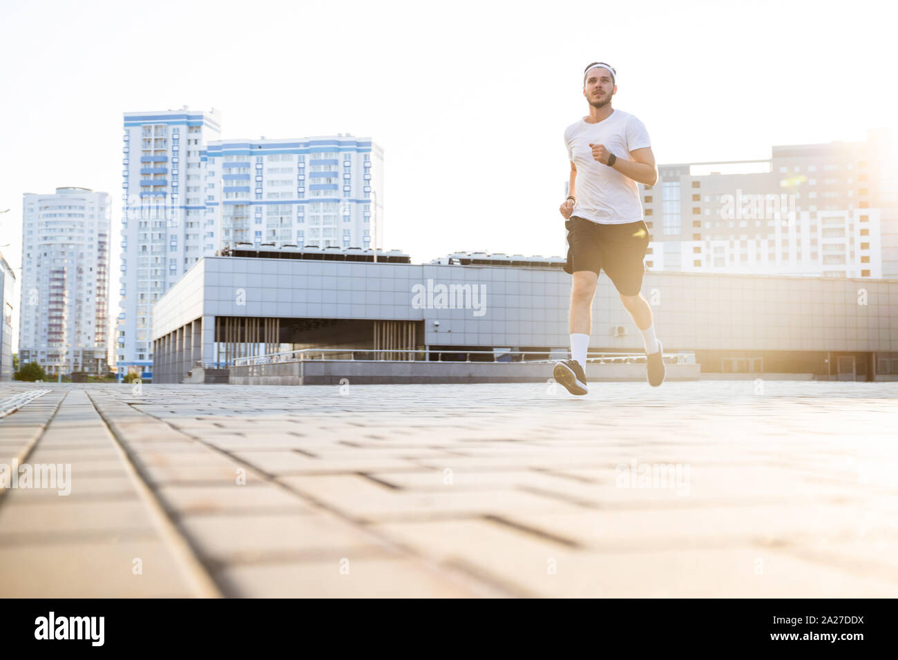 Attractive fit man running in the city at sunset. Fitness, workout ...