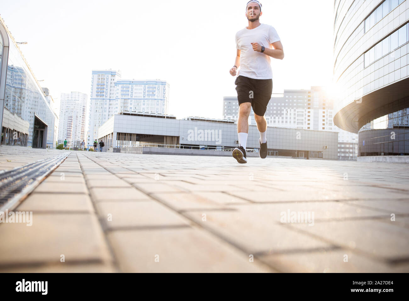 Attractive fit man running in the city at sunset. Fitness, workout ...