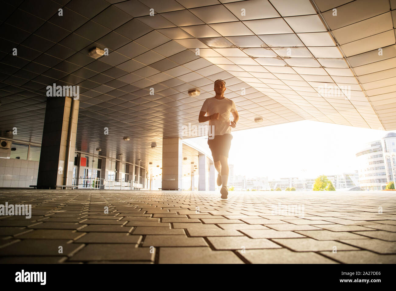 Attractive fit man running in the city at sunset. Fitness, workout ...