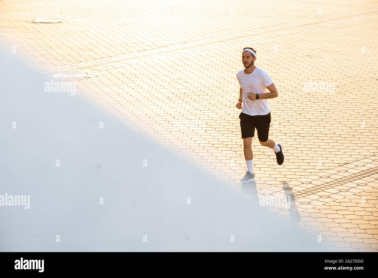 Attractive fit man running in the city at sunset. Fitness, workout ...
