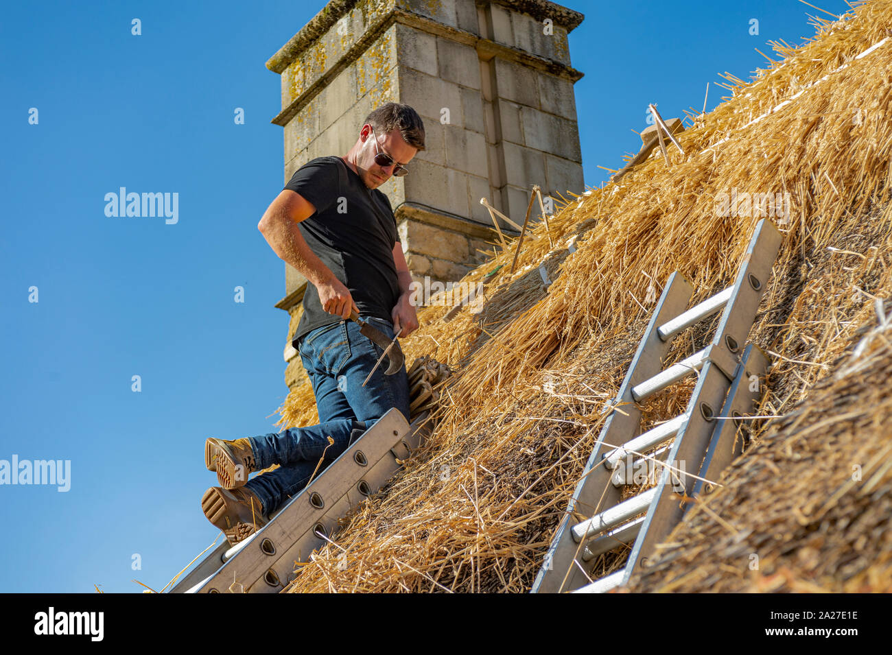 A thatcher working on the roof of a village cottage repairing and ...