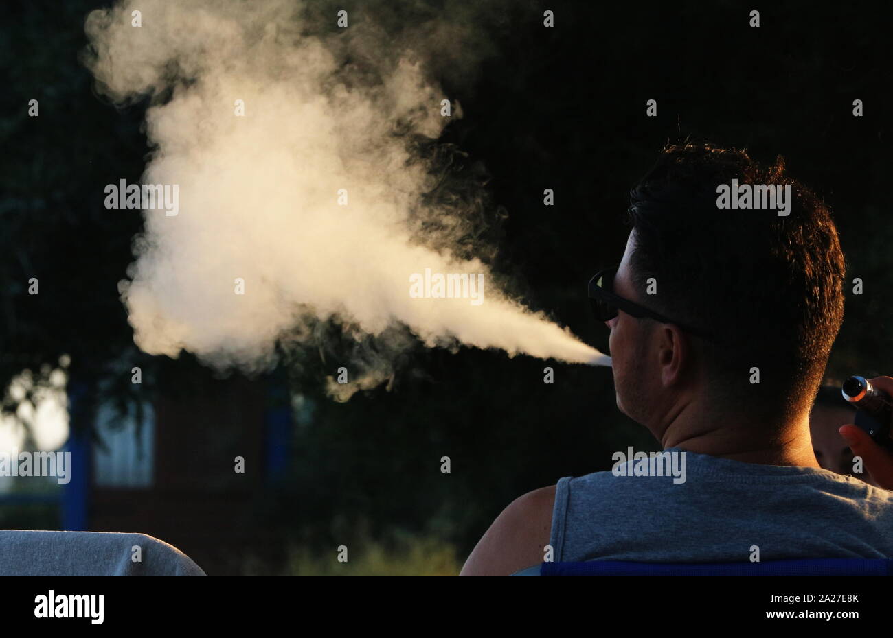 Man blowing big cloud of smoke from vaping Stock Photo - Alamy
