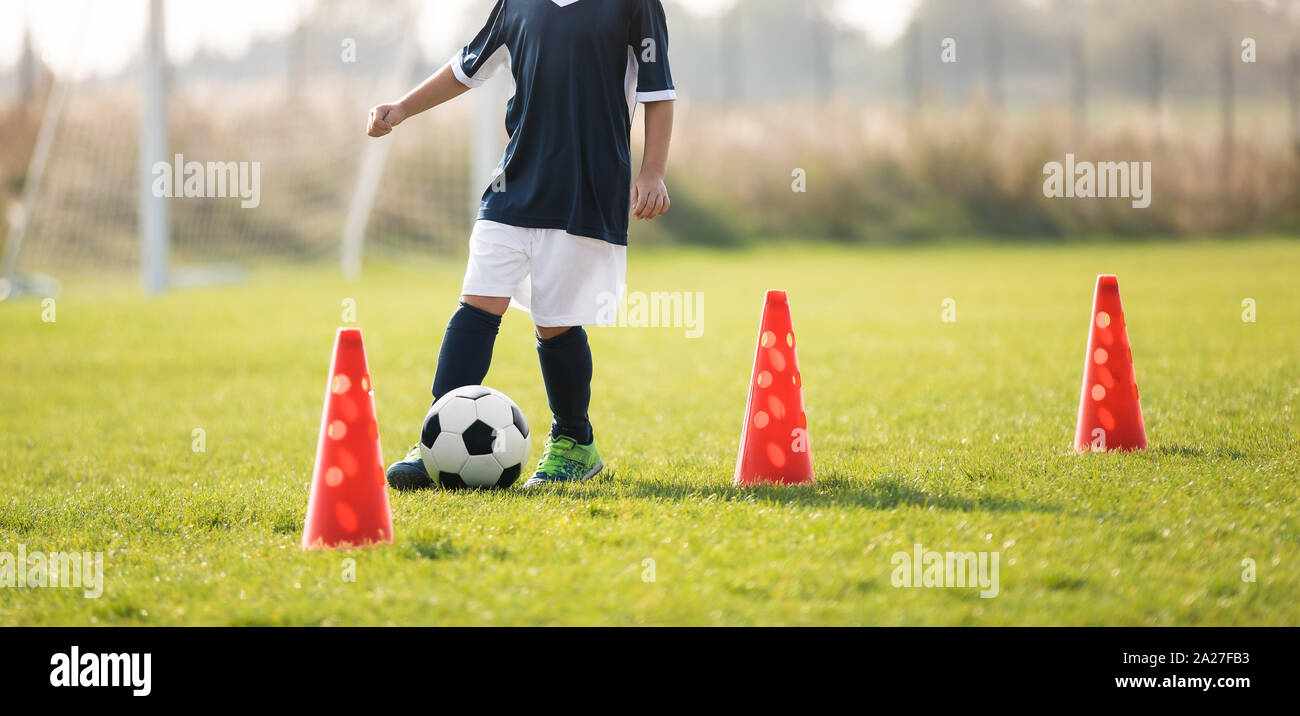 Soccer player dribbling through cones in the ground on a sunny. Young ...