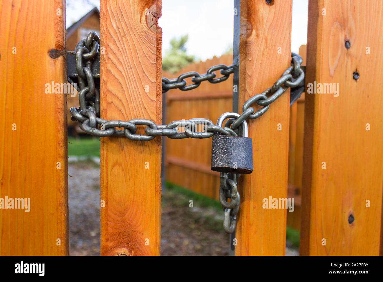 Padlock and steel thick chain on a bright yellow wooden fence Stock ...