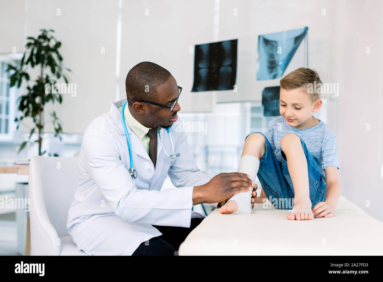 African man doctor first aid examines child boy patient's leg sprain ...