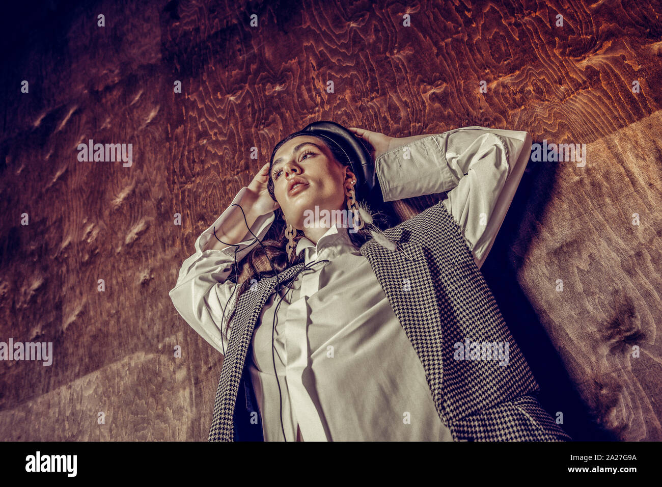 Low angle of the pretty lady with closed eyes leaning on the wall Stock ...