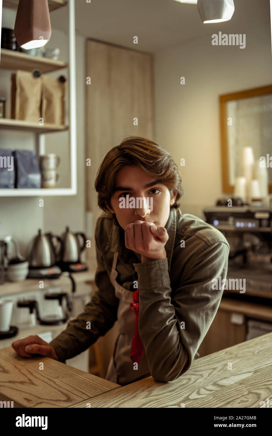 Portrait of an attractive young male leaning on bar counter looking ...