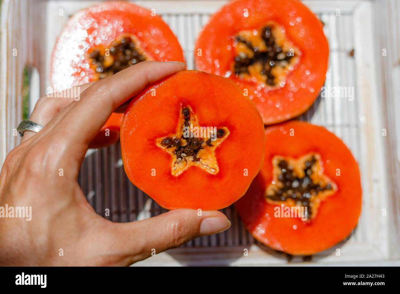 Fresh papaya cut in round pieces, with a star shape middle. Female hand ...