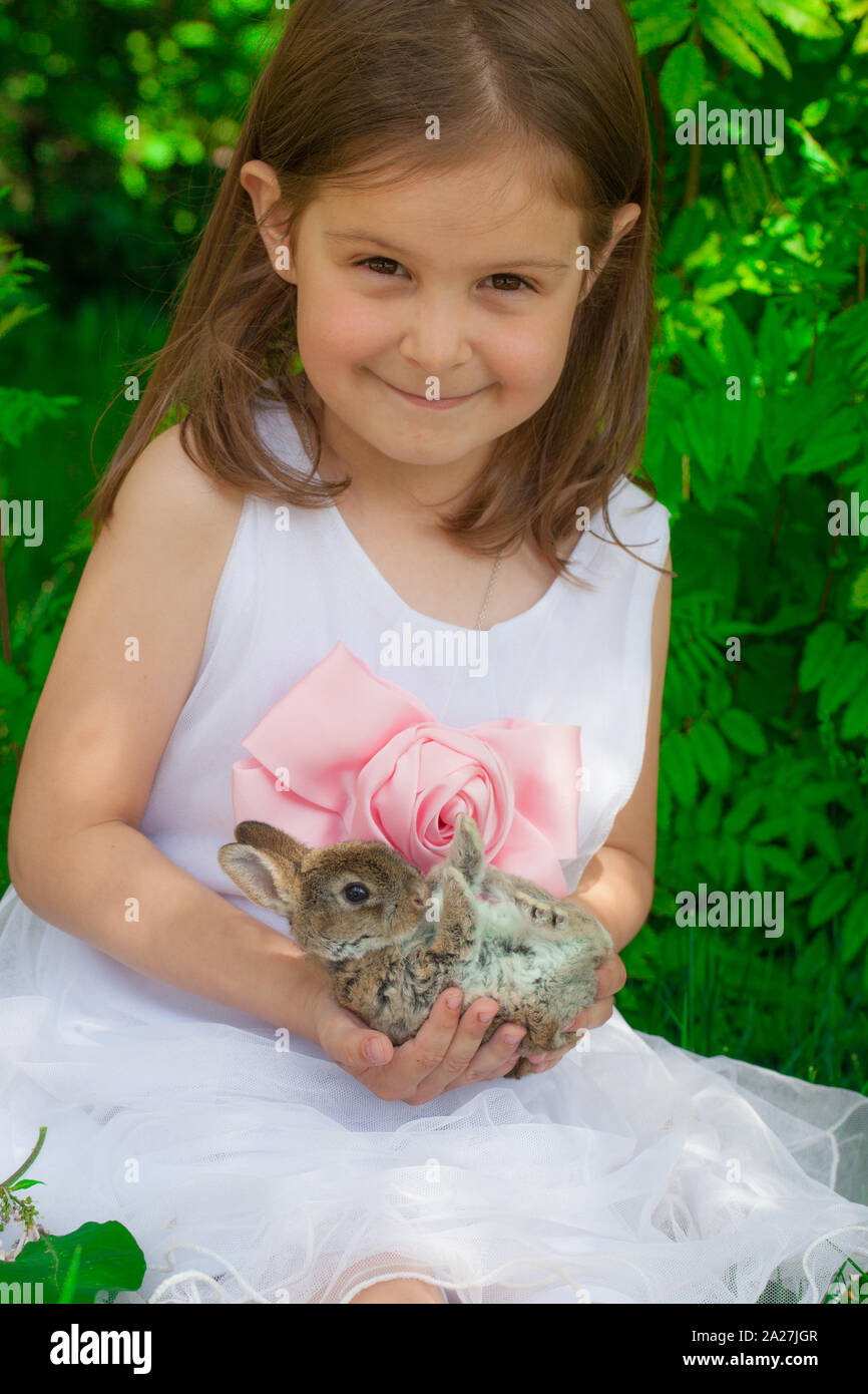 Little girl holding a rabbit. Porter child with a hare in his hands ...