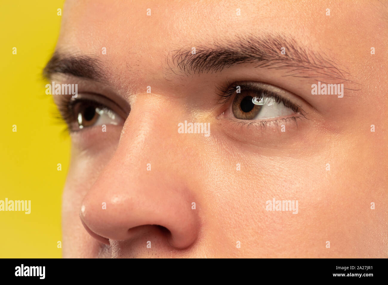 Caucasian young man's close up portrait on yellow studio background ...
