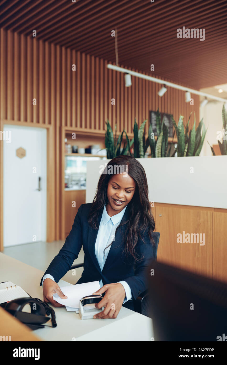 Smiling young African American businesswoman organizing paperwork while ...