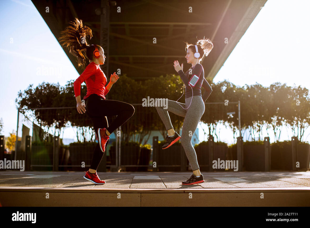 Two young women doing gymnastic exercises outdoor in urban enviroment ...