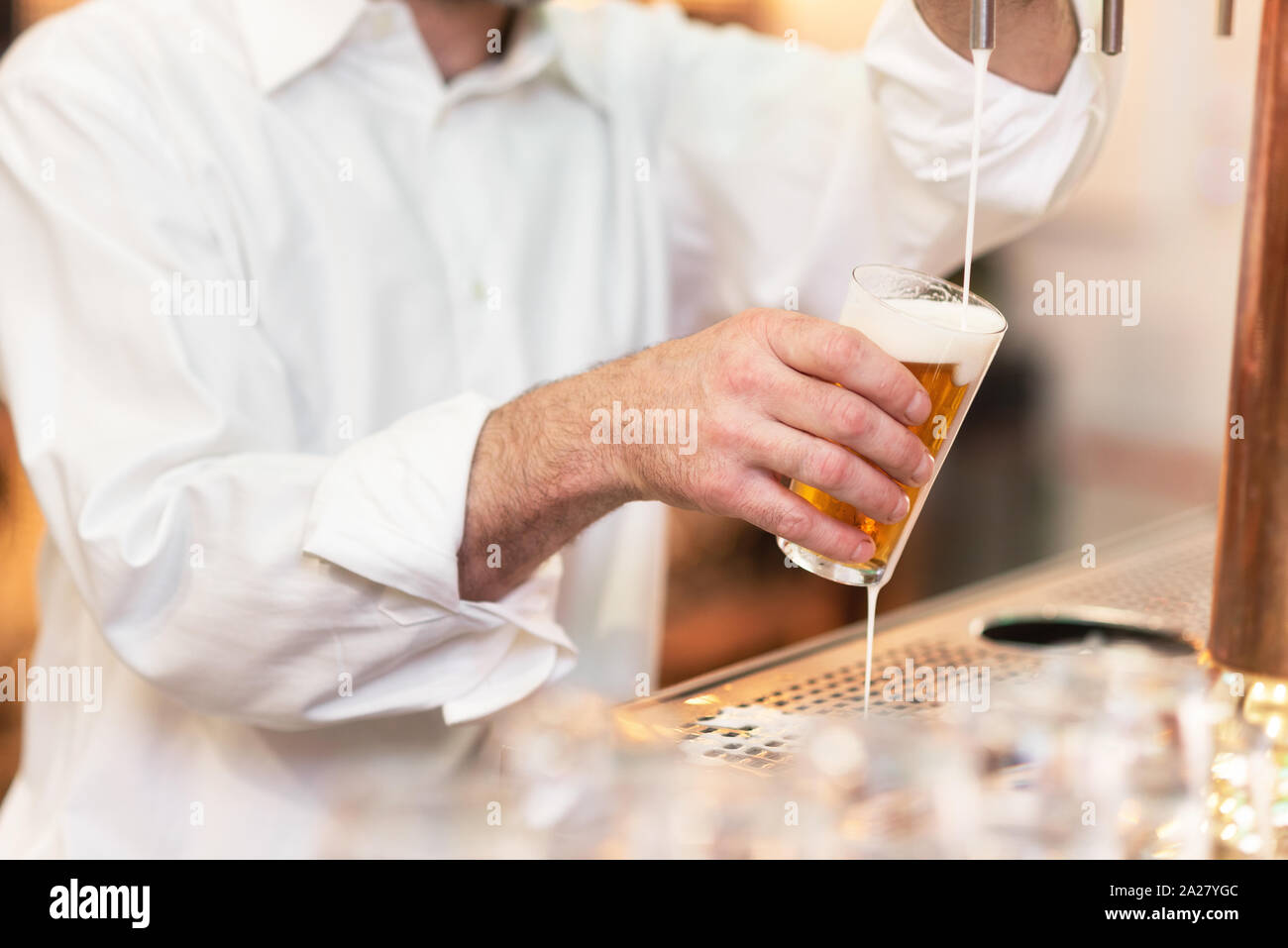 Pouring beer for client. Bartender pouring beer while standing at the ...