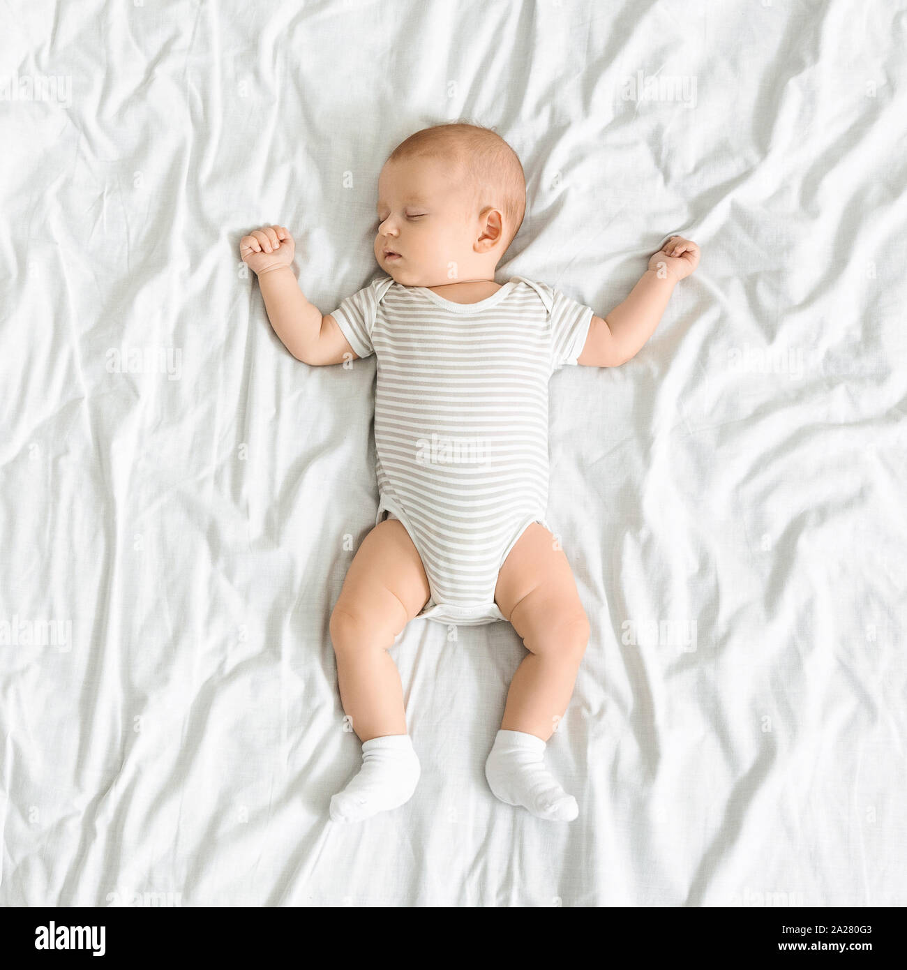 Adorable newborn baby napping in bed with arms up Stock Photo - Alamy