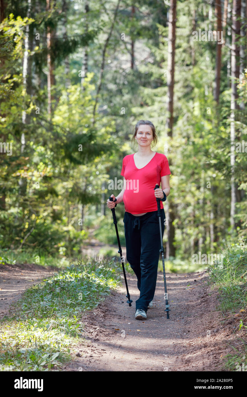 Young pregnant woman walking along a trail through the forest during ...