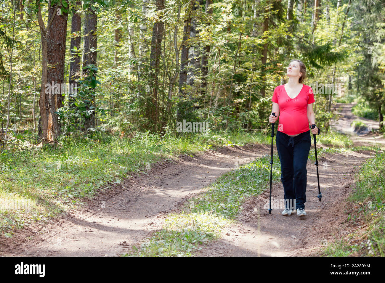 Young pregnant woman walking along a trail through the forest during ...