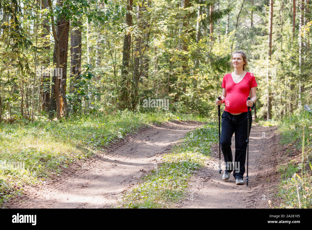 Young pregnant woman walking along a trail through the forest during ...