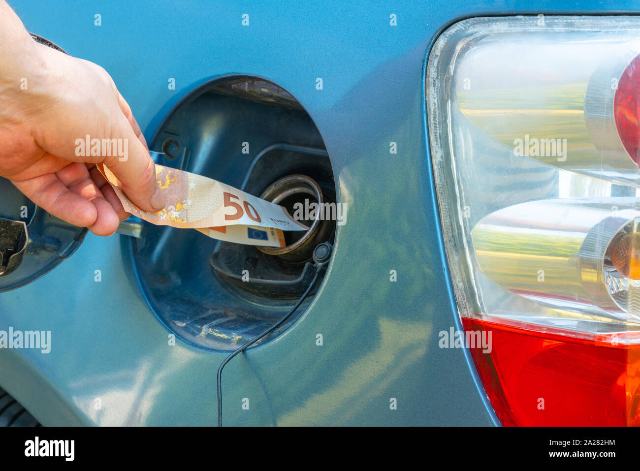 Hand putting Euro money bills in car fuel tank. Transportation expenses ...