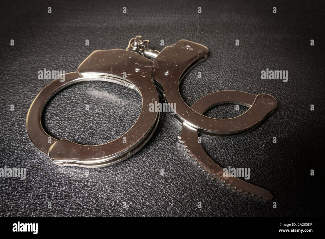 Open handcuffs on a black table close-up Stock Photo - Alamy