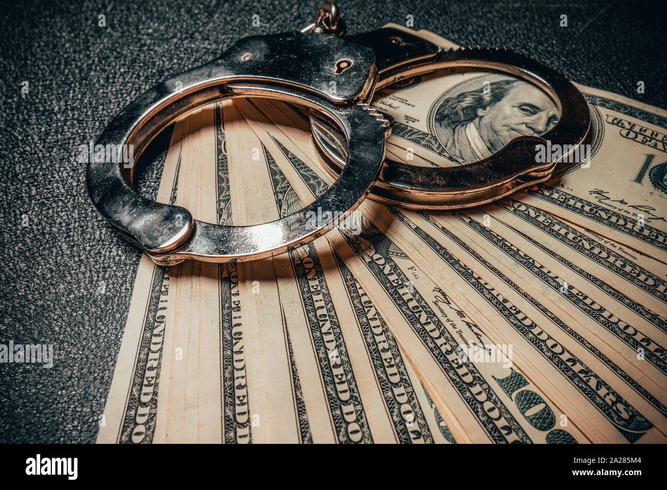 Handcuffs on hundred dollar american banknotes on black background. The ...