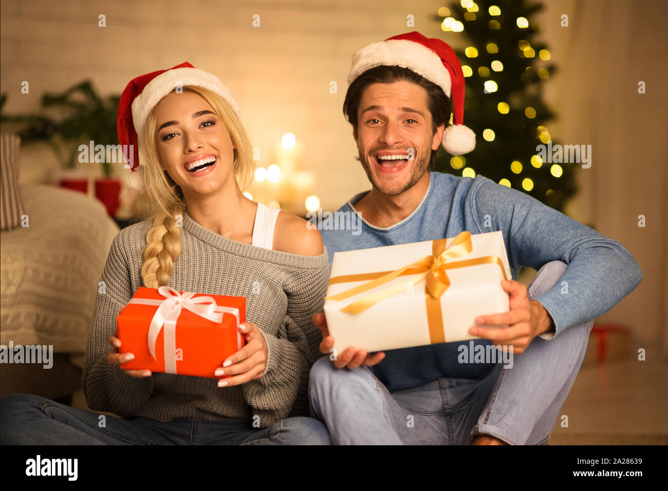 Celebrating Christmas together. Couple holding gift boxes Stock Photo ...