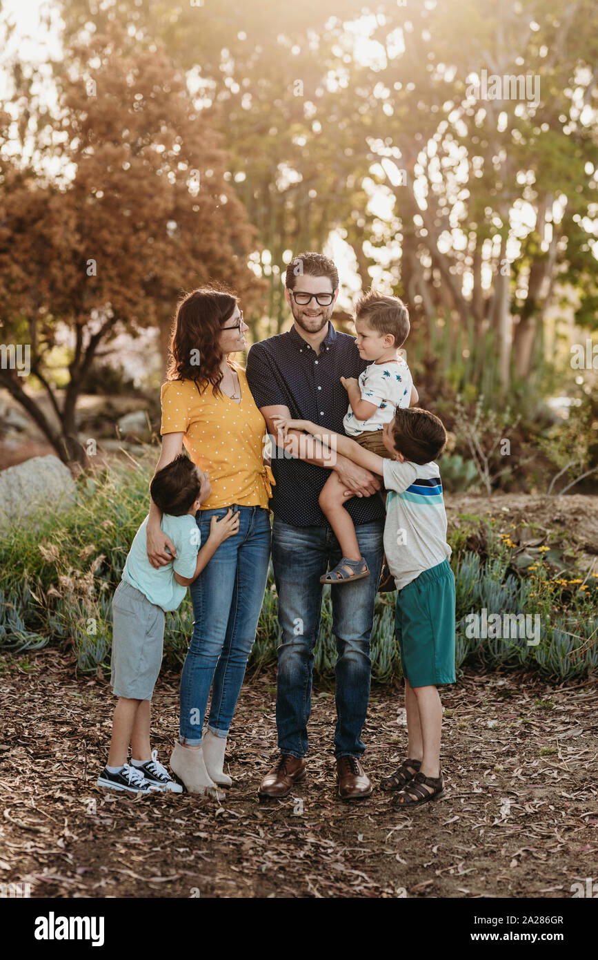Portrait of family smiling at each other and hugging in cactus garden ...
