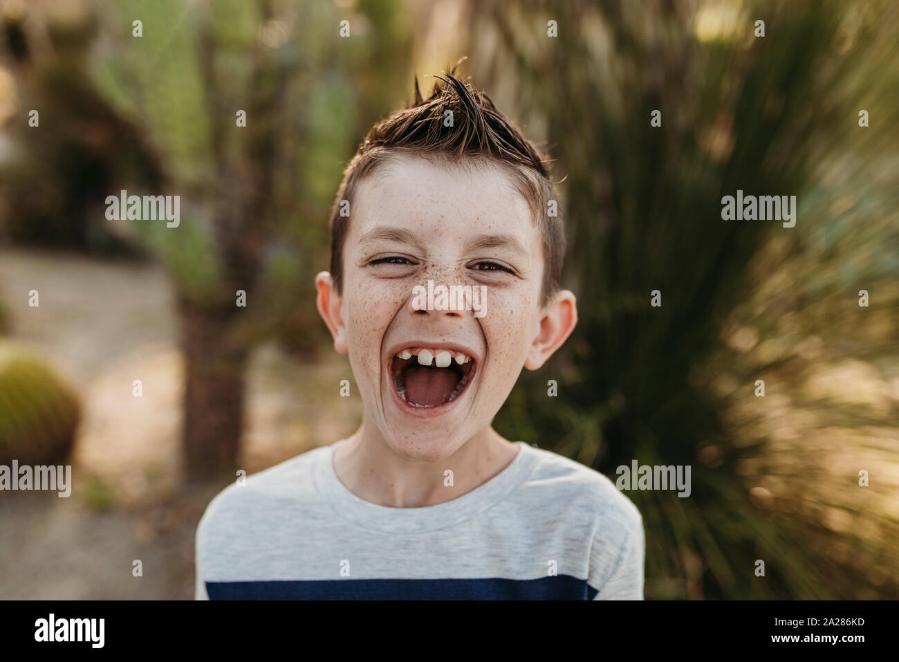 Close up portrait of cute young boy with freckles laughing outdoors ...