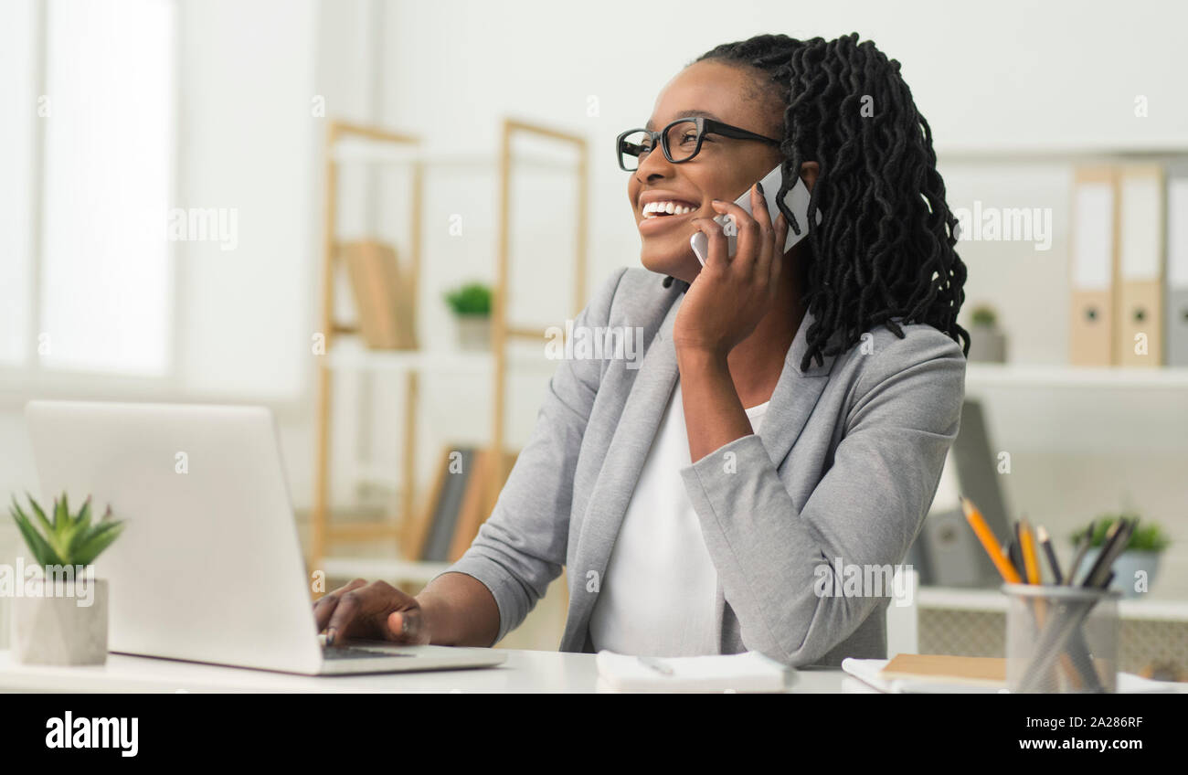 Happy Office Girl Talking On Phone Using Laptop Indoor Stock Photo - Alamy