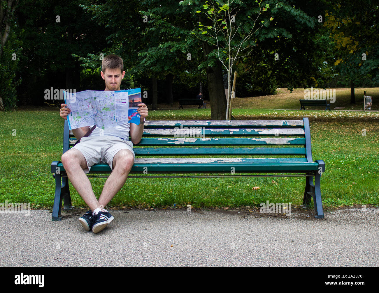 Boy looking at a map on a bench Stock Photo - Alamy