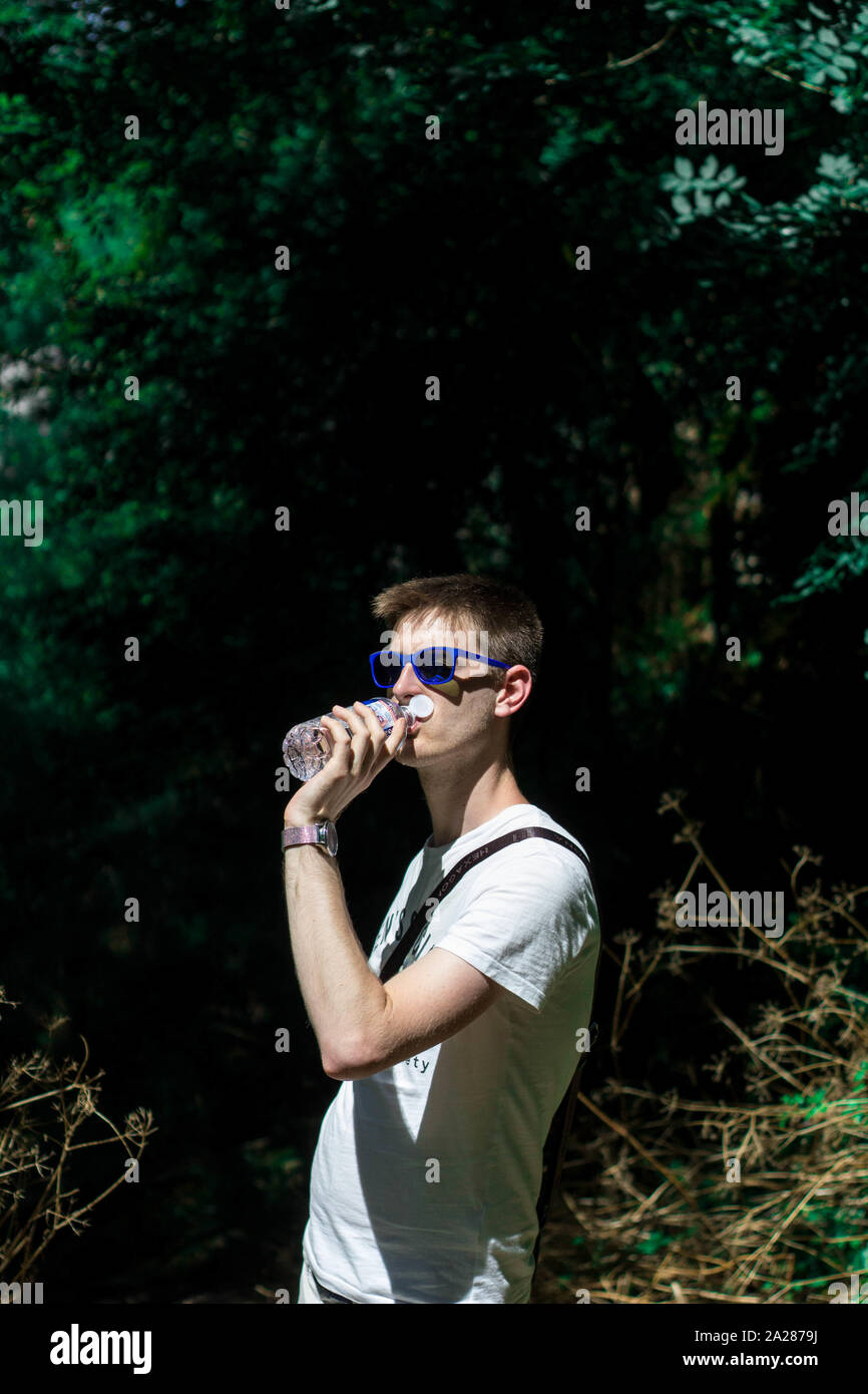 young boy drinking water in a forest with trees Stock Photo - Alamy