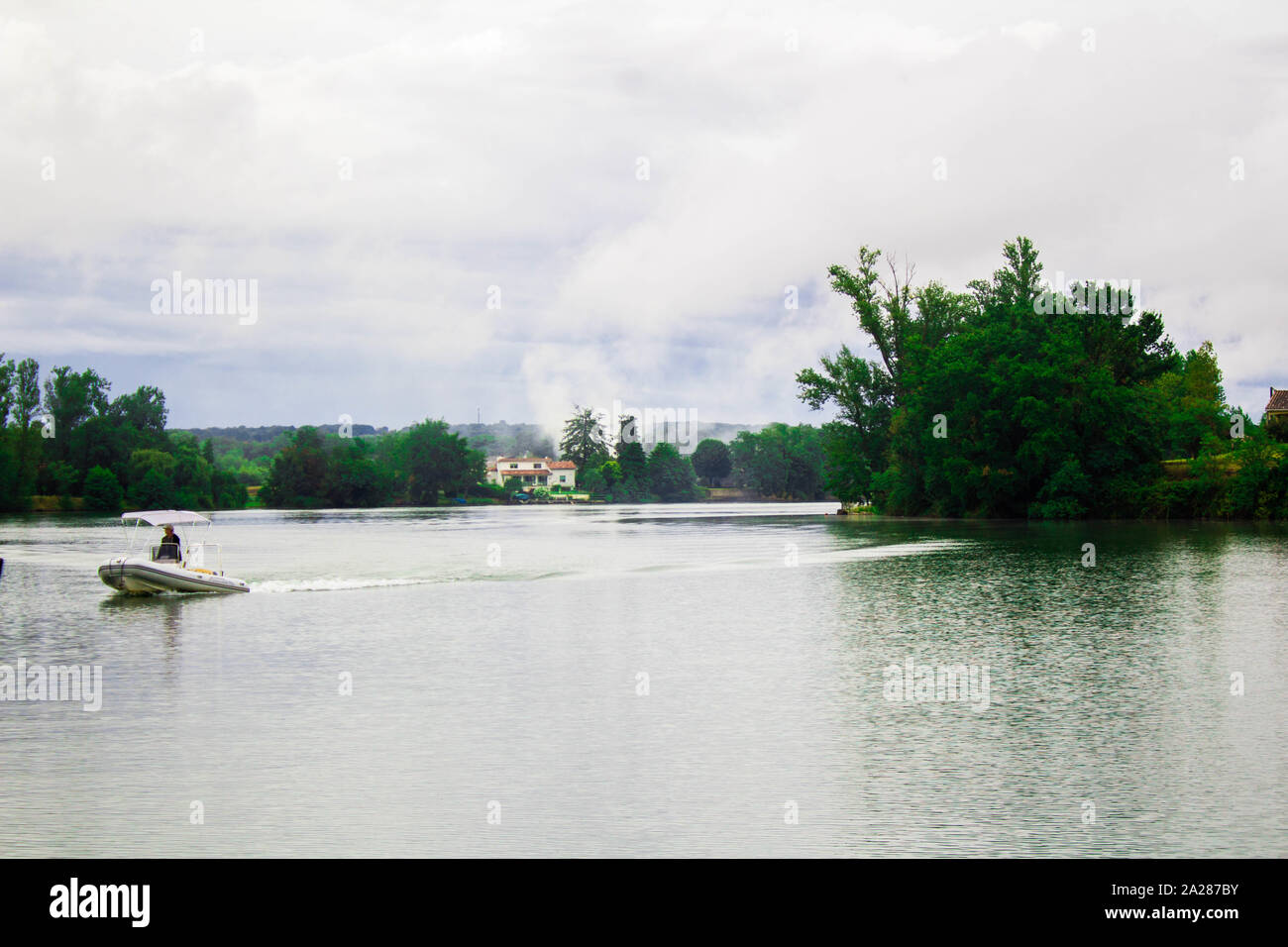 boat sailing on a river, in the background a house with vegetation ...