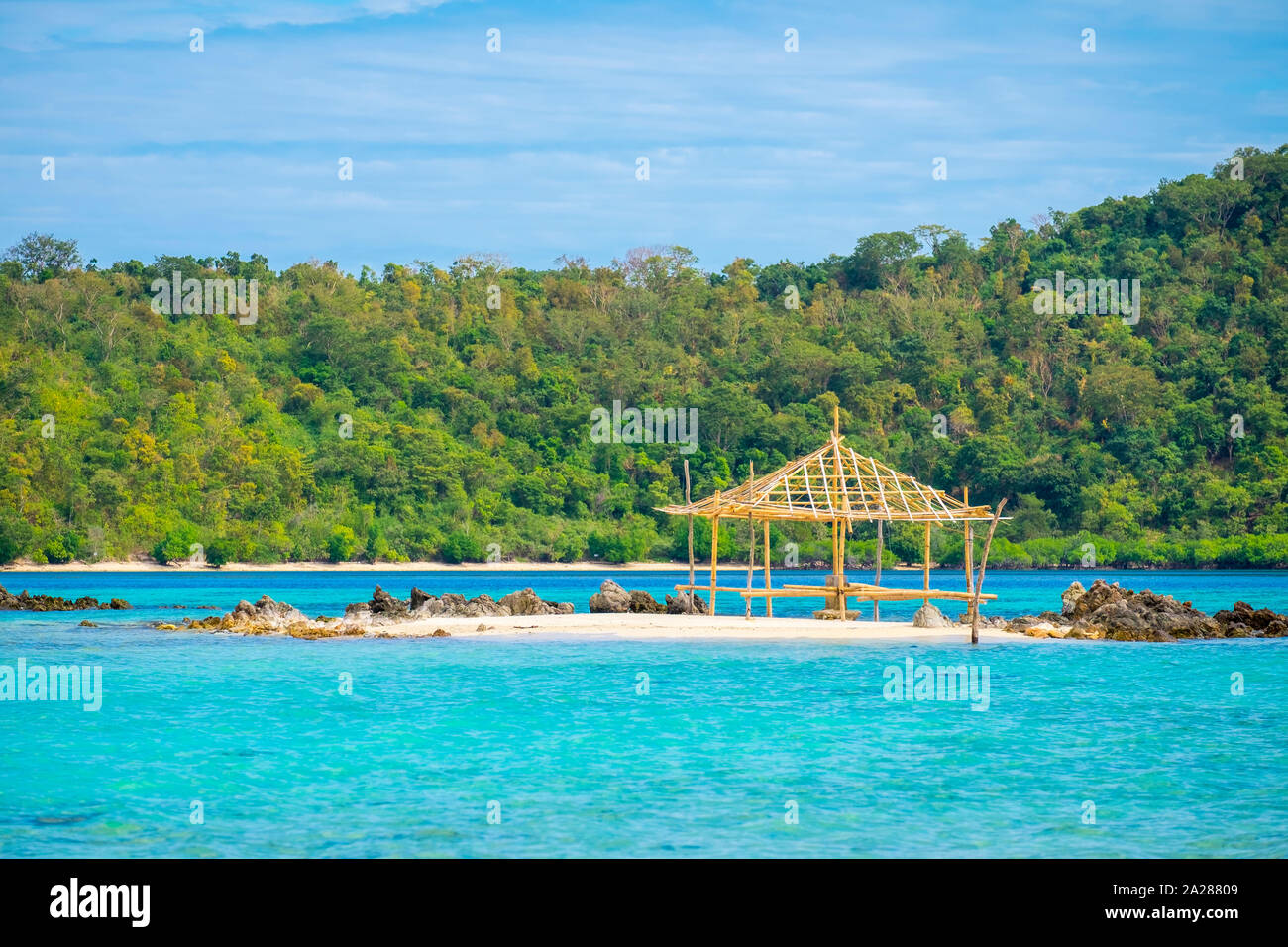 Bamboo structure on small rocky beach in blue water at Banana Island ...