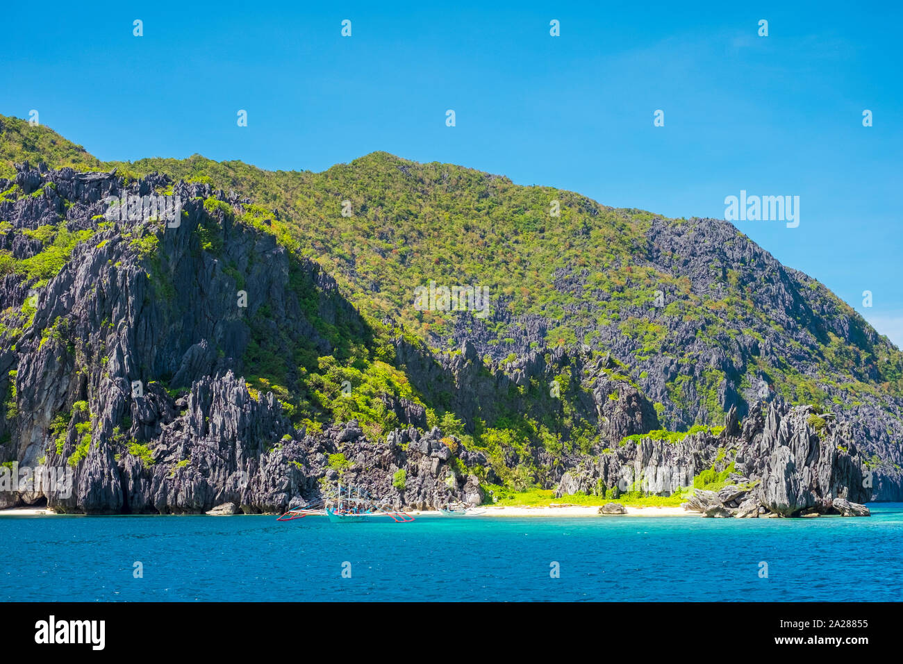 Boats anchored near a small beach on Tapiutan Island, El Nido, Palawan ...